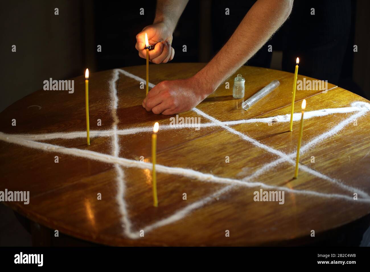 Men's hands set candles on the pentagram symbol Stock Photo - Alamy