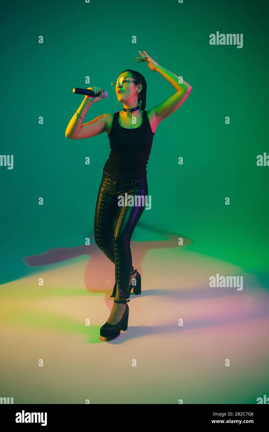 Caucasian female singer portrait isolated on green studio background in ...