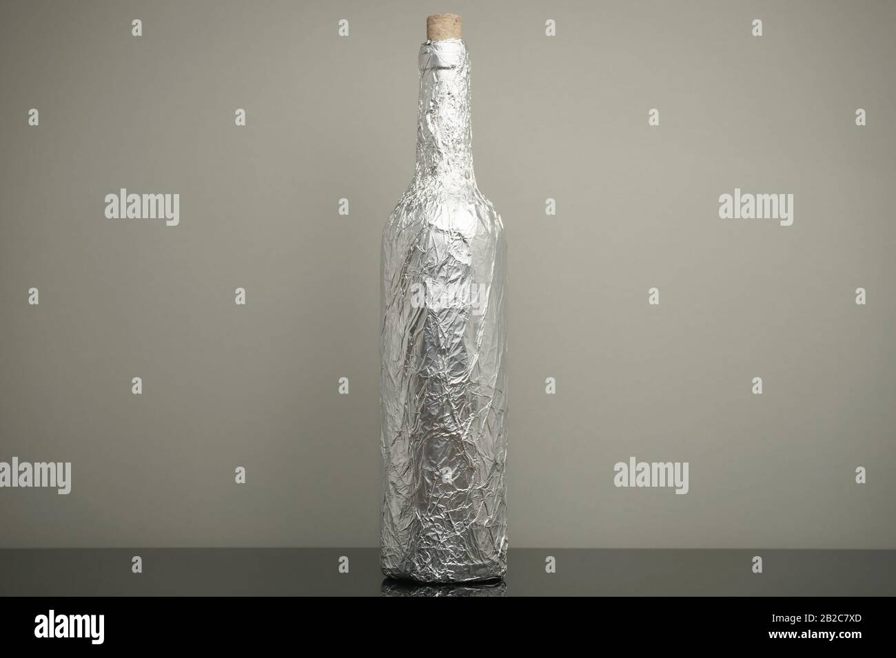 Bottle of wine wrapped in foil on a dark glass table gray background ...