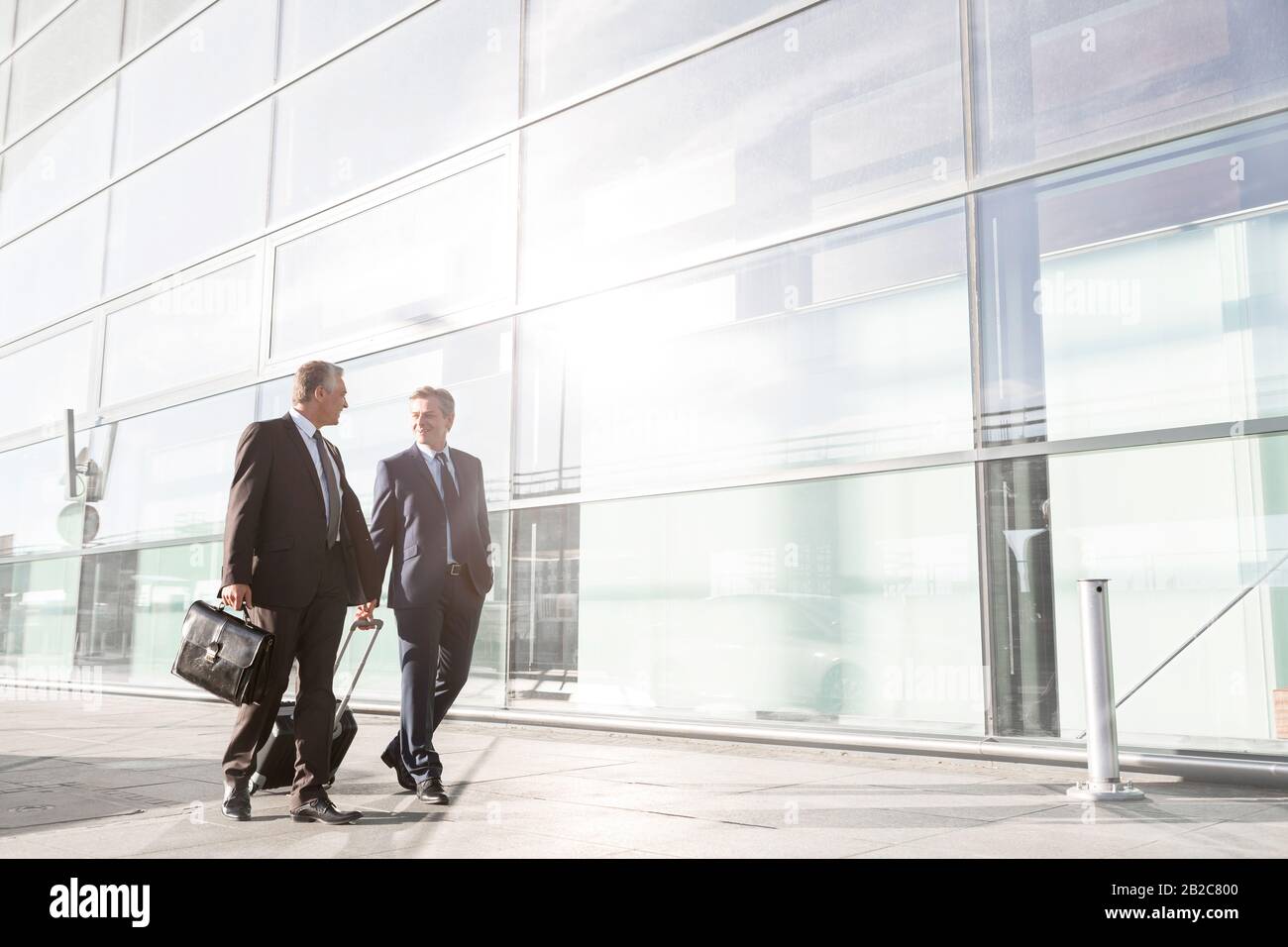 Mature businessmen walking while talking in the airport Stock Photo - Alamy