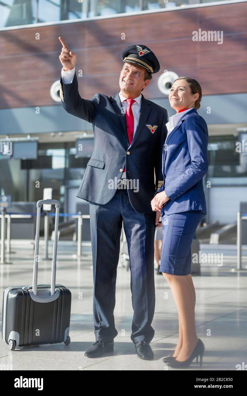 Pilot pointing aircraft while talking to flight attendant in airport ...