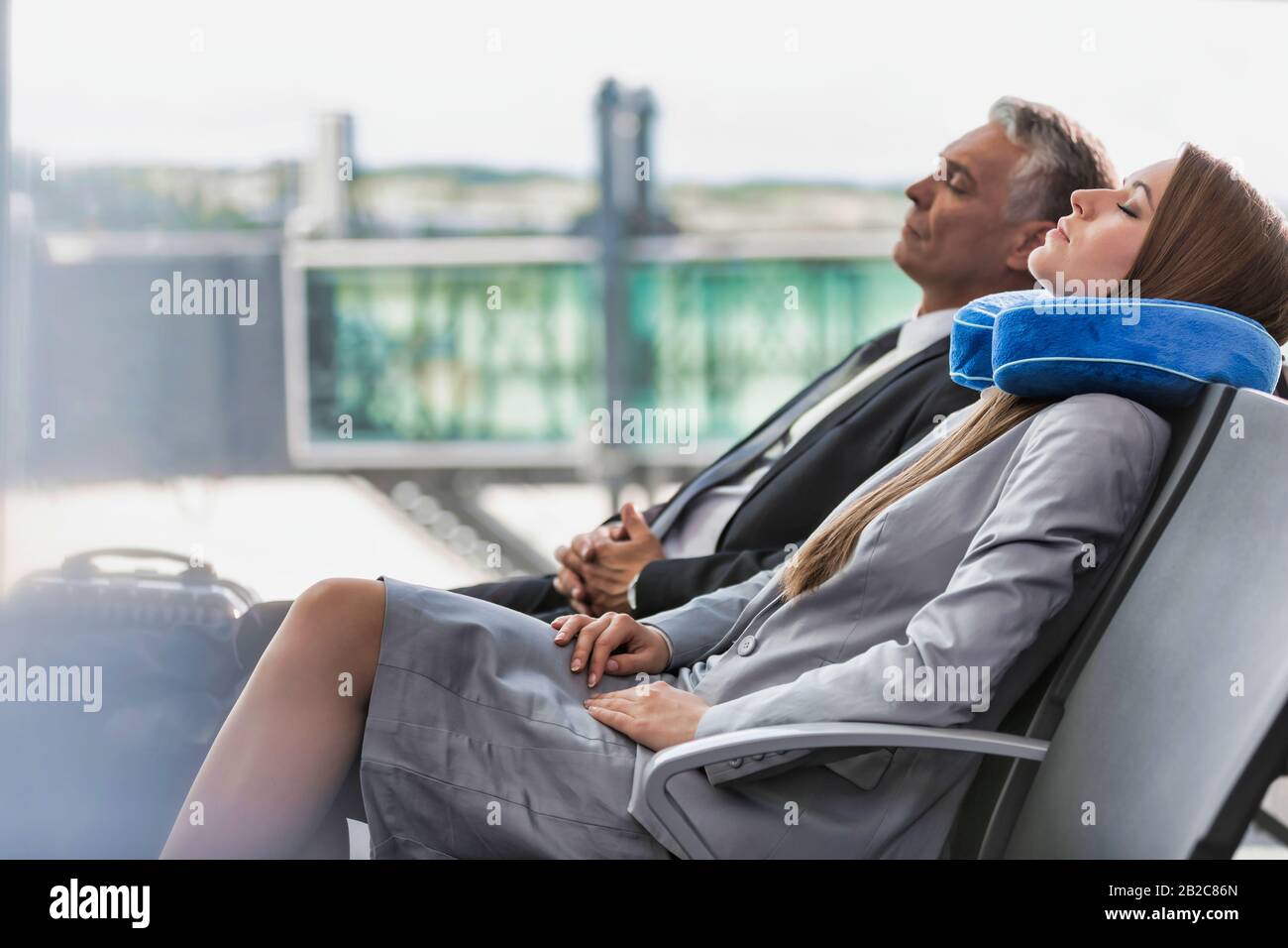 Mature businessman and young attractive businesswoman sleeping while waiting for boarding in ...