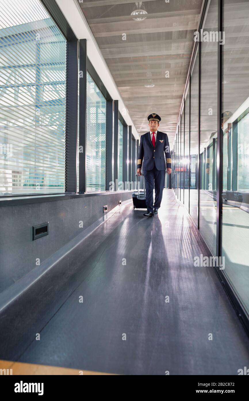 Portrait of mature pilot walking with his suitcase in airport Stock ...
