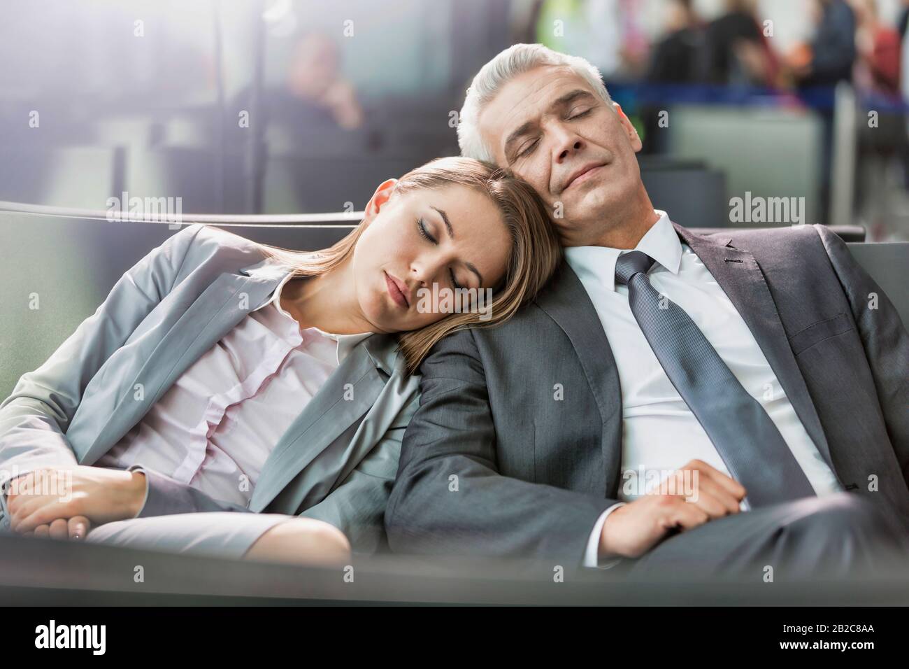 Portrait of business couple sleeping while waiting for boarding in airport with lens flare Stock ...