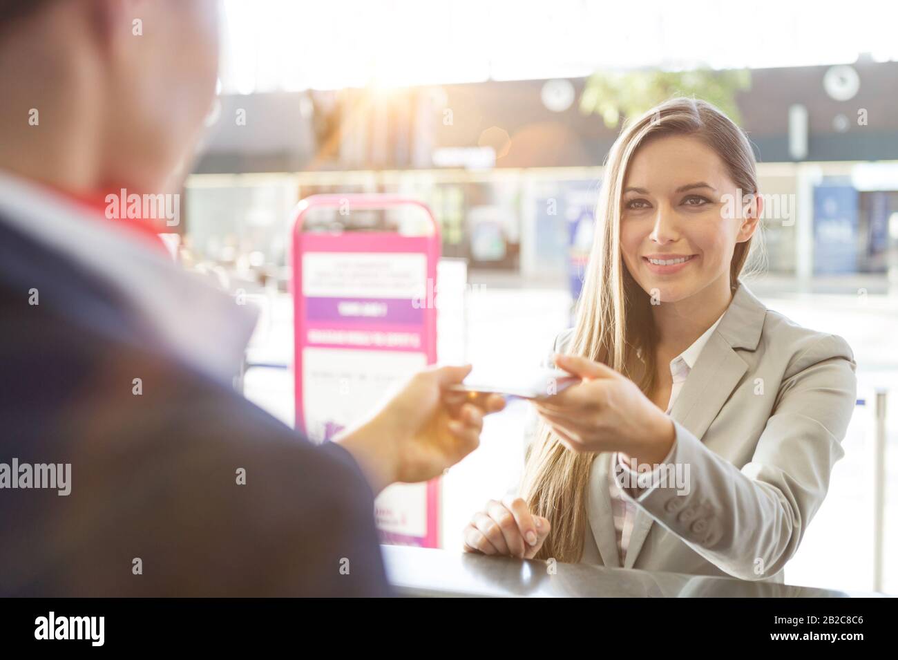 Passenger service agent giving woman's passport and boarding pass in ...