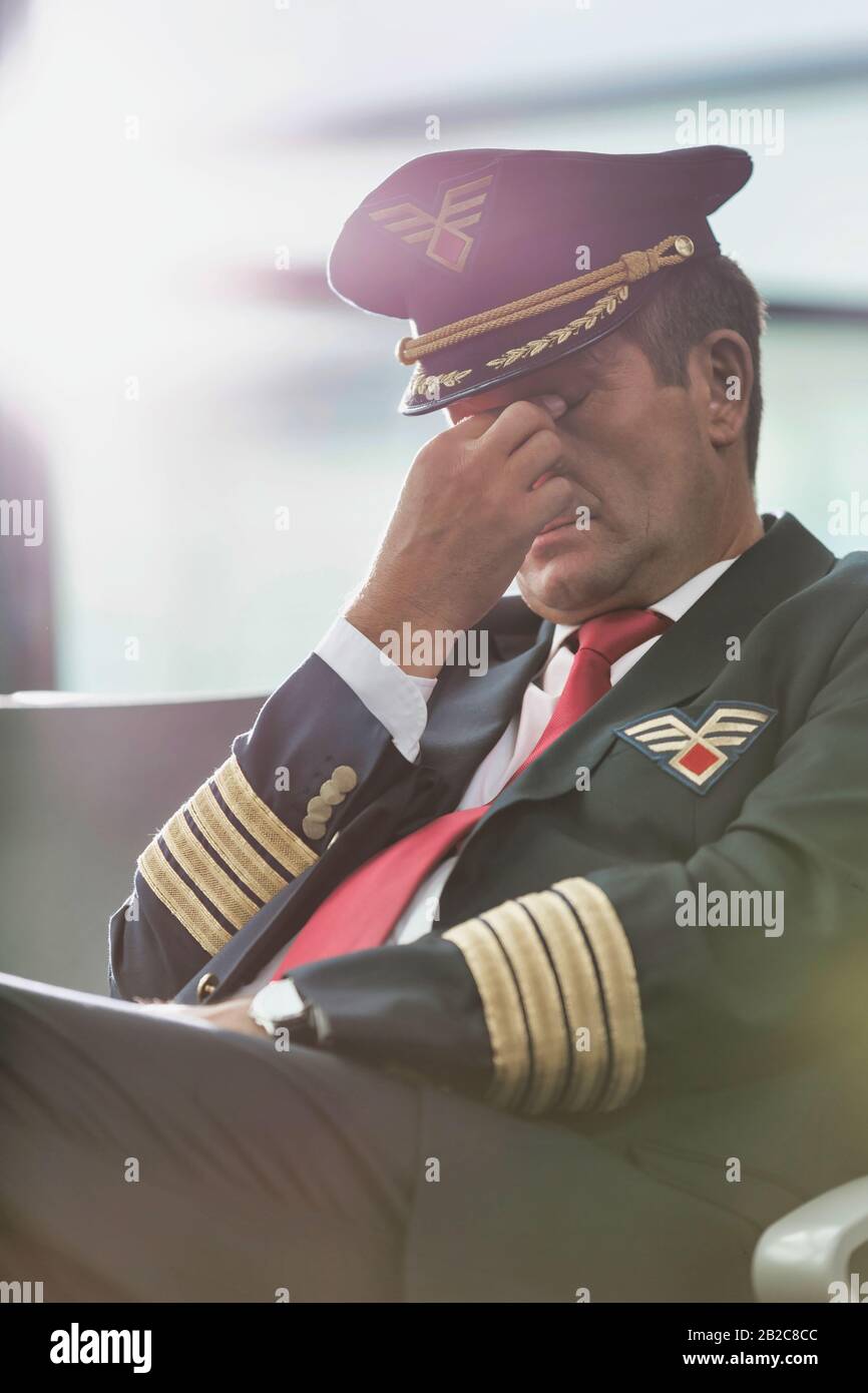 Portrait of sleepy and overworked pilot sitting in airport Stock Photo ...