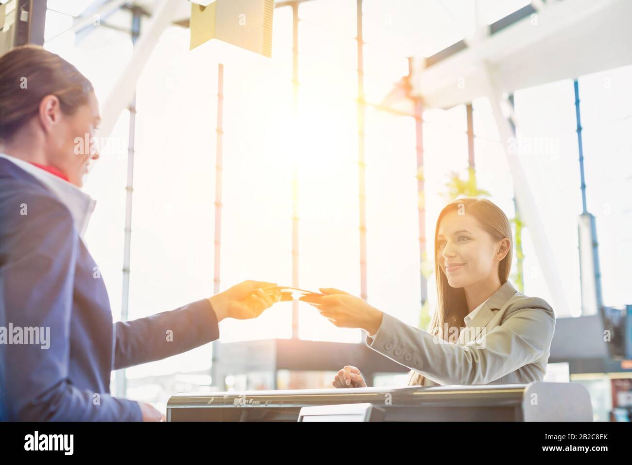 Passenger service agent giving boarding pass to young attractive ...