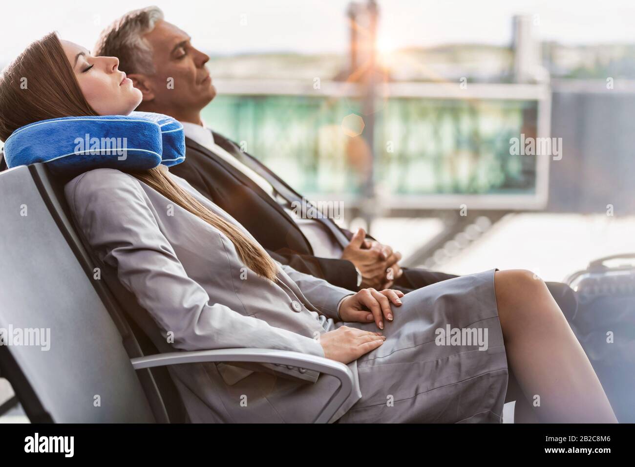 Mature businessman and young attractive businesswoman sleeping while waiting for boarding in ...