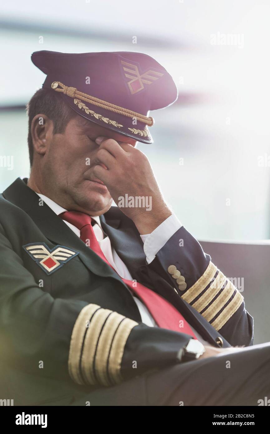 Portrait of sleepy and overworked pilot sitting in airport Stock Photo ...