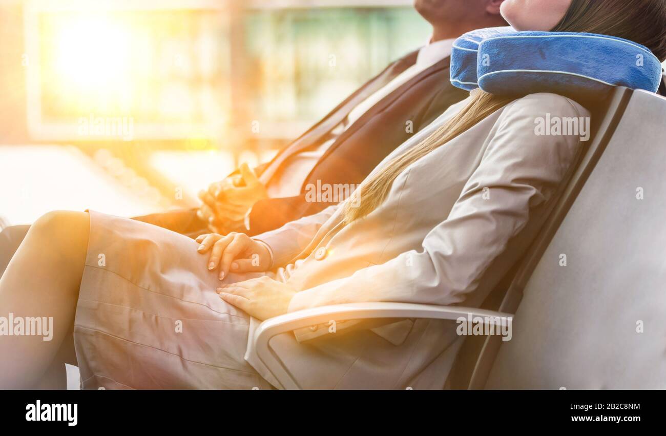 Mature businessman and young attractive businesswoman sleeping while waiting for boarding in ...