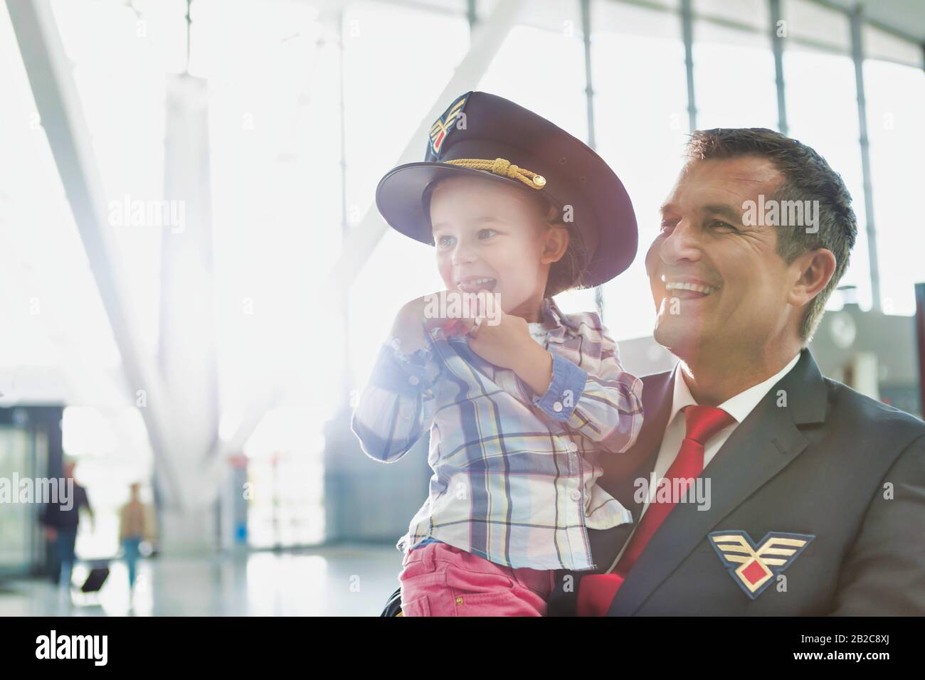 Portrait of mature pilot carrying cute little child in airport Stock ...