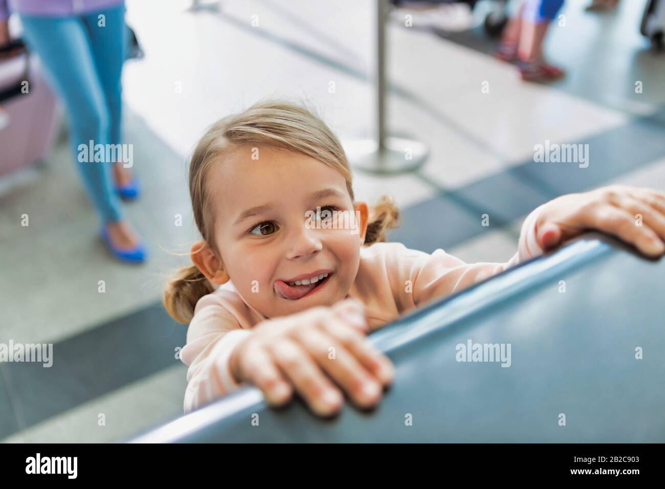 Portrait of young cute little girl being playful in check in at airport ...