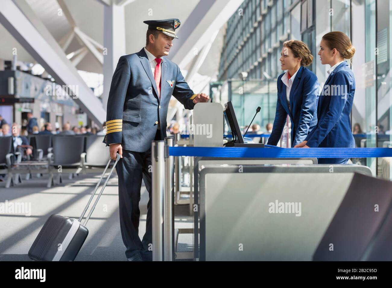Portrait of mature pilot talking with the airport staffs in boarding ...