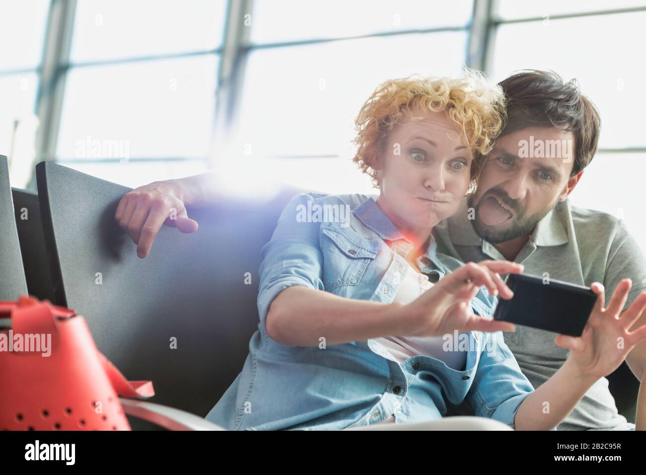 Portrait Of Mature Couple Taking Selfie While Waiting For Boarding In