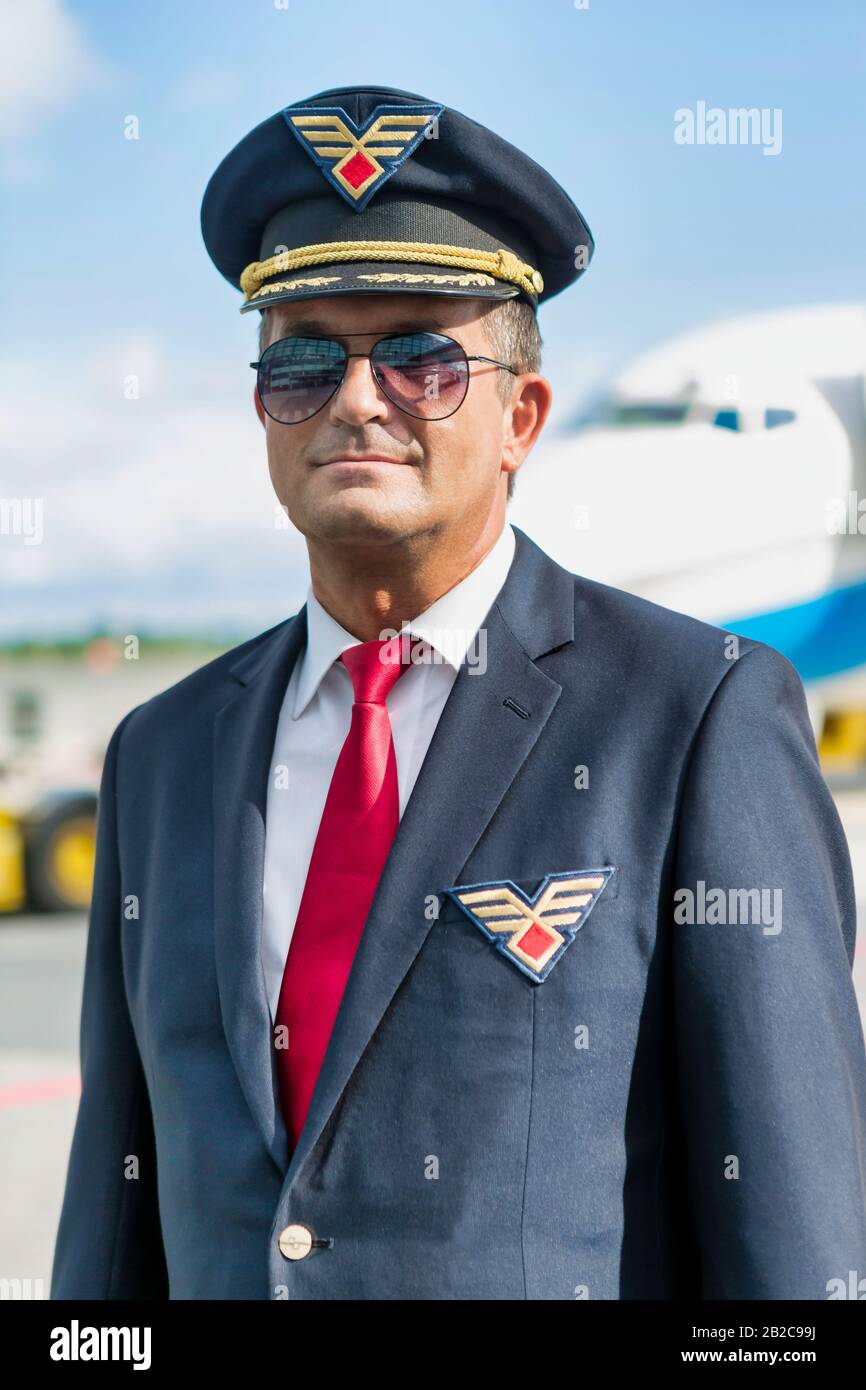 Portrait of mature pilot standing against airplane in airport Stock ...