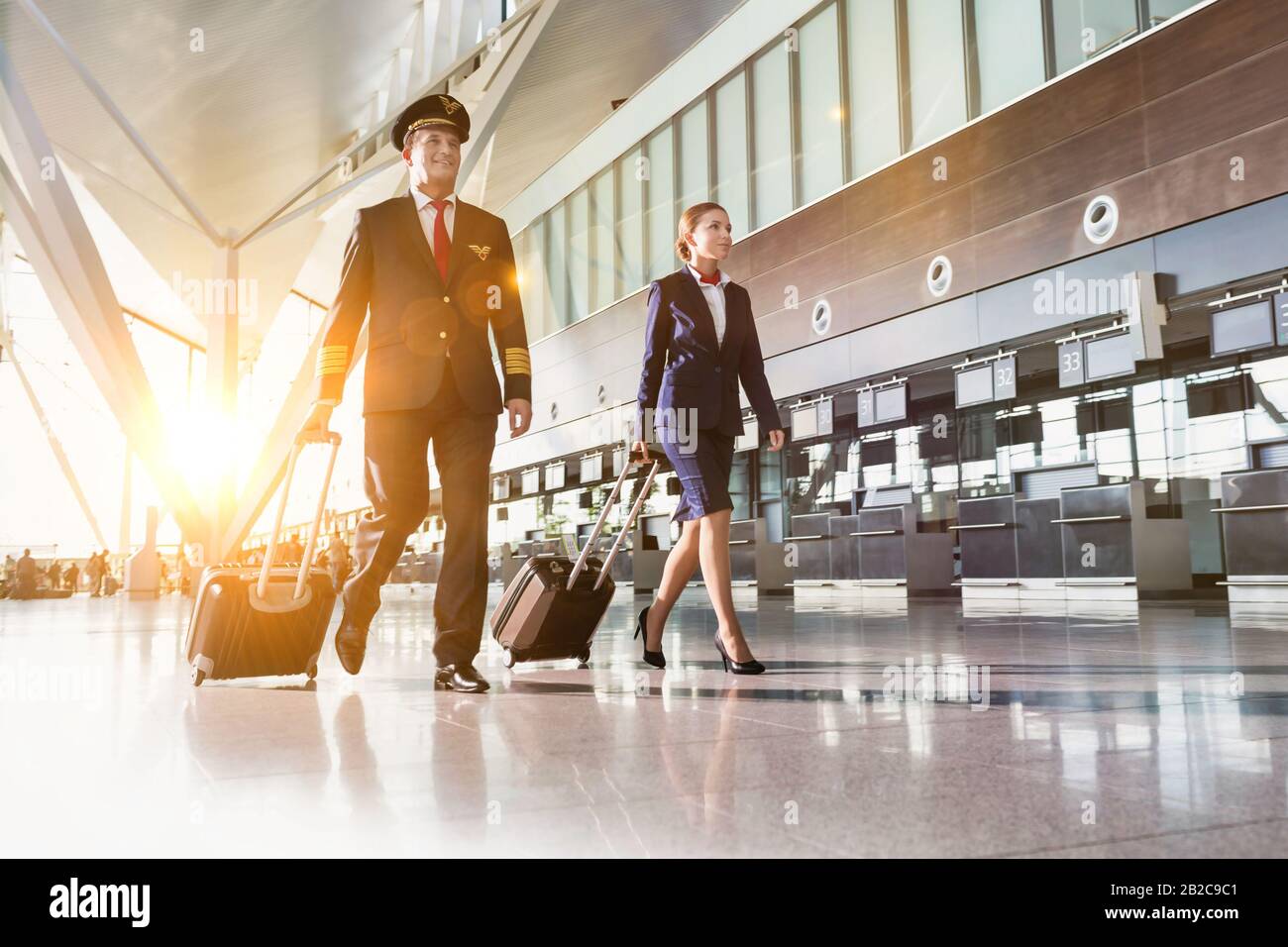 Portrait of confident pilot with stewardess walking in airport Stock ...