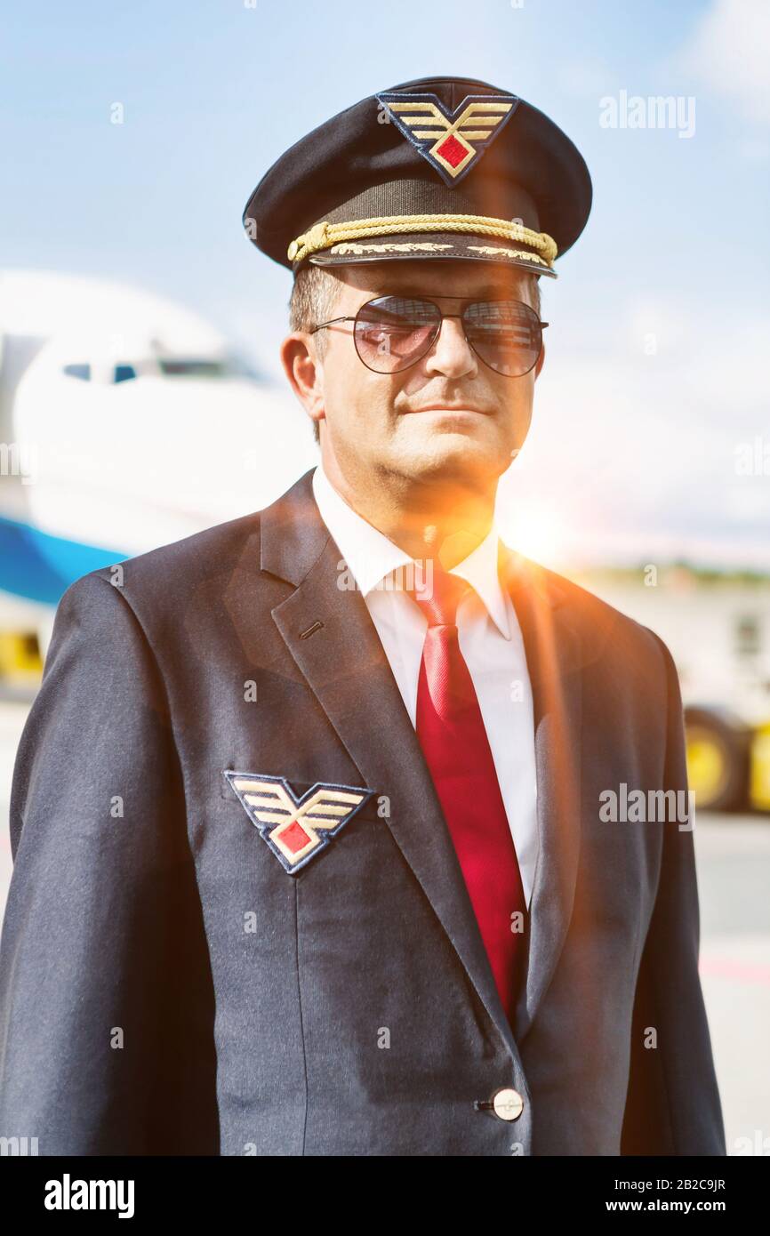 Portrait of mature pilot standing against airplane in airport Stock ...