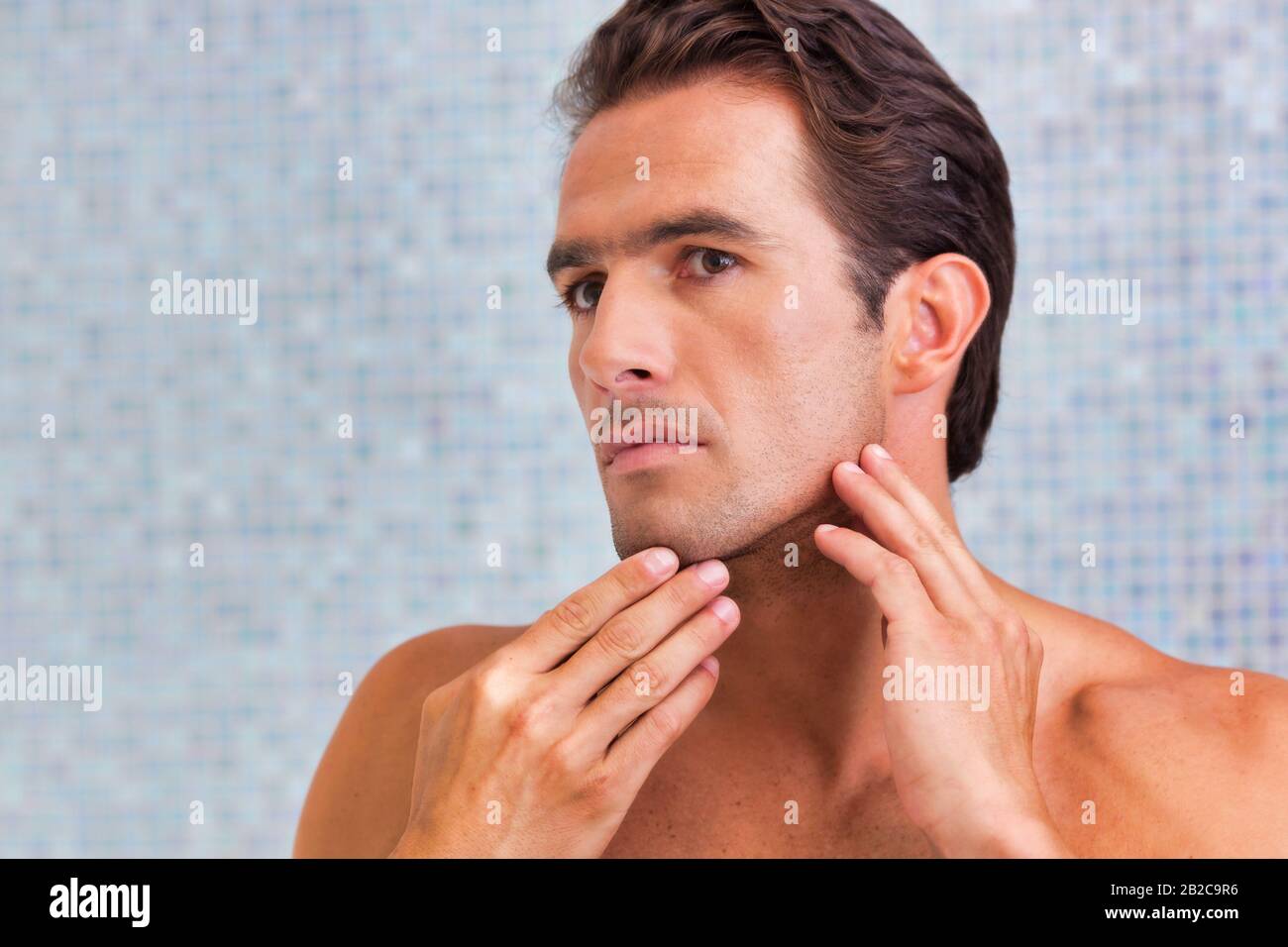 Attractive man checking his face in the bathroom mirror Stock Photo - Alamy