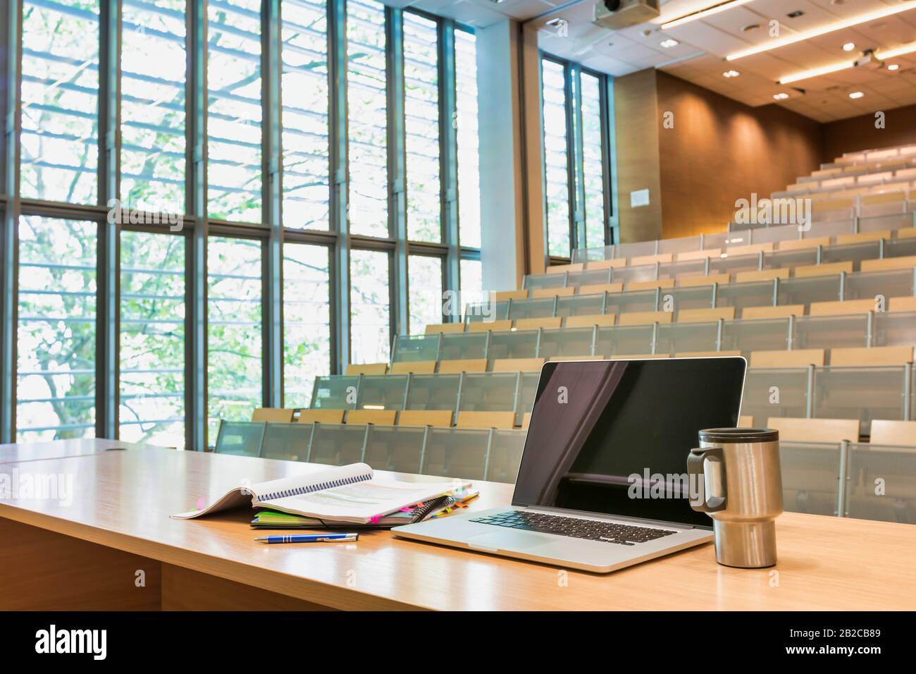 Photo of laptop on professor desk with tumbler in classroom Stock Photo ...