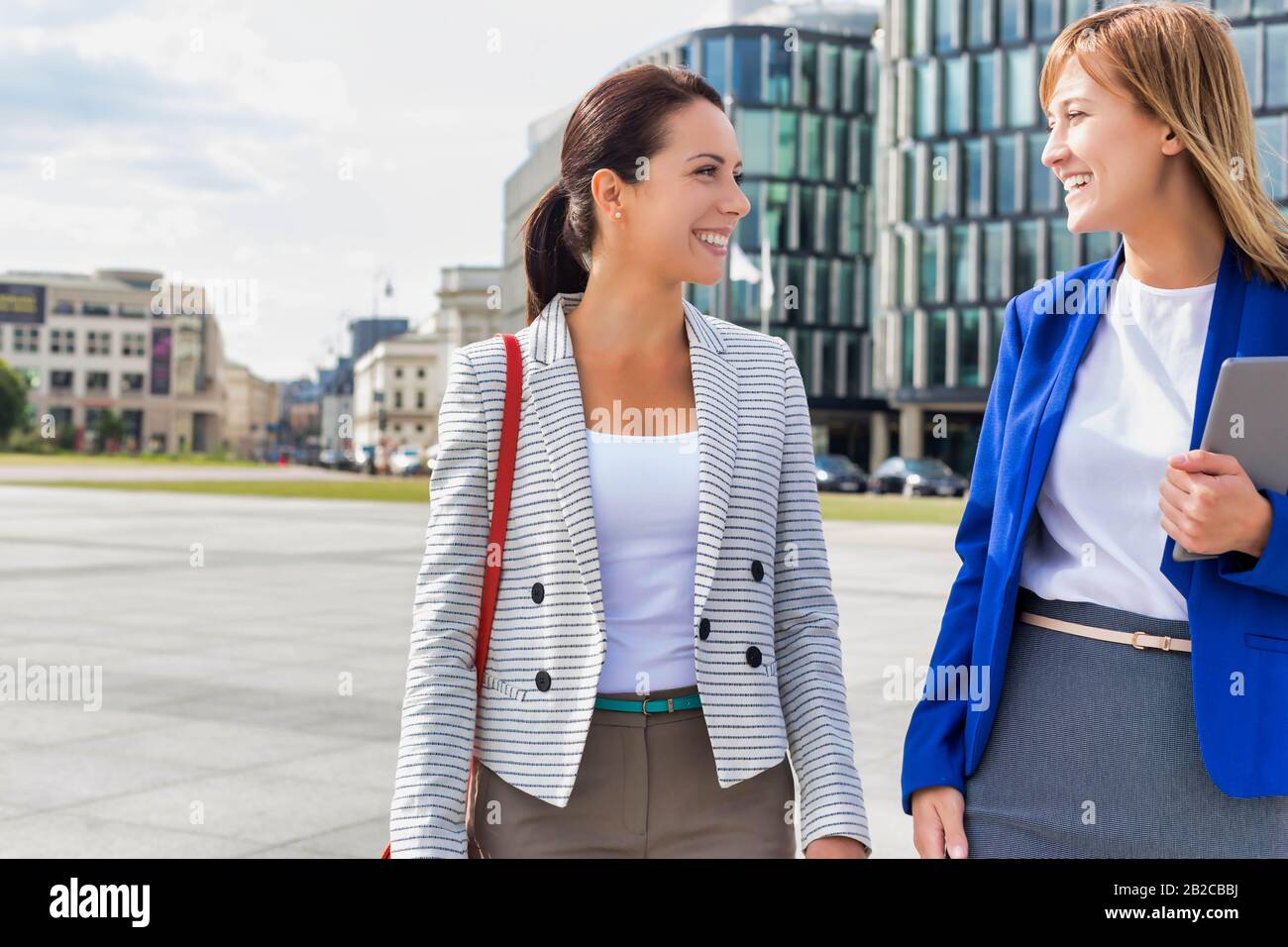 Businesswomen walking while talking outside office building Stock Photo ...