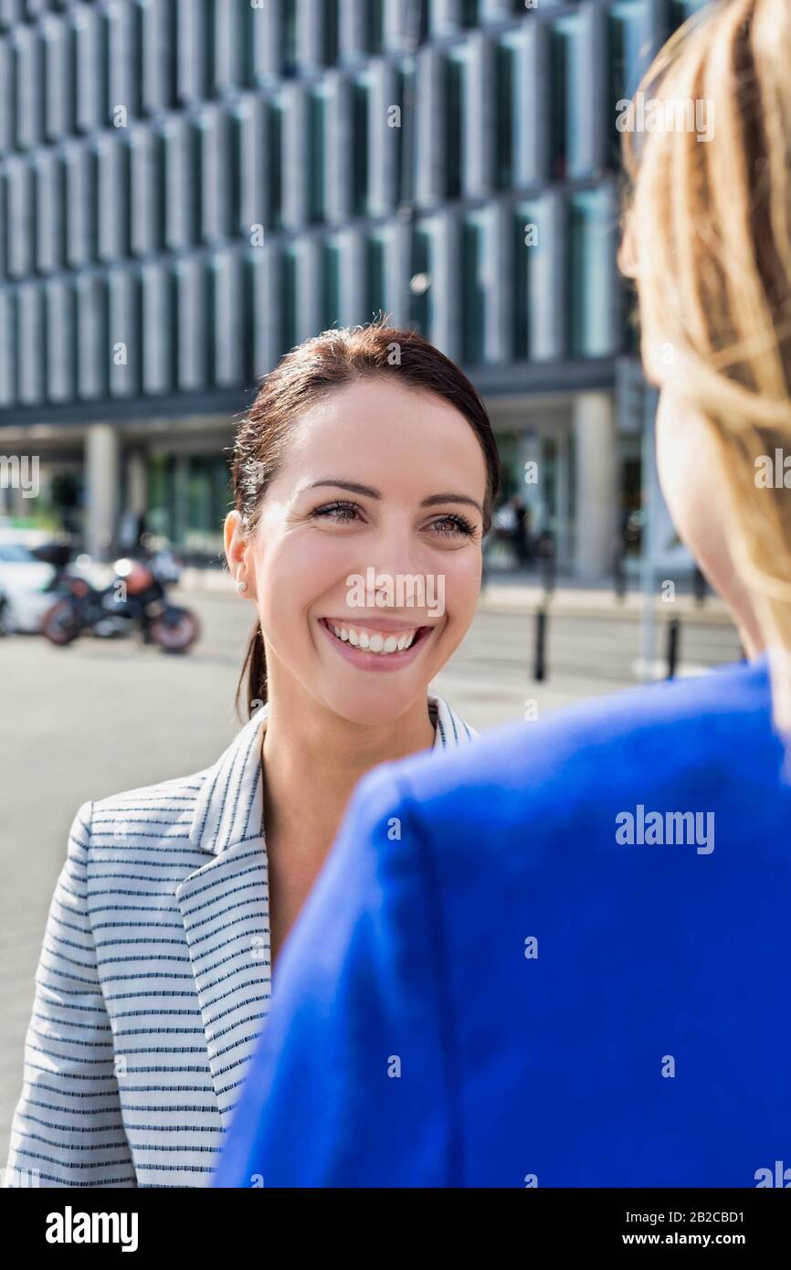 Businesswomen walking while talking outside office building Stock Photo ...