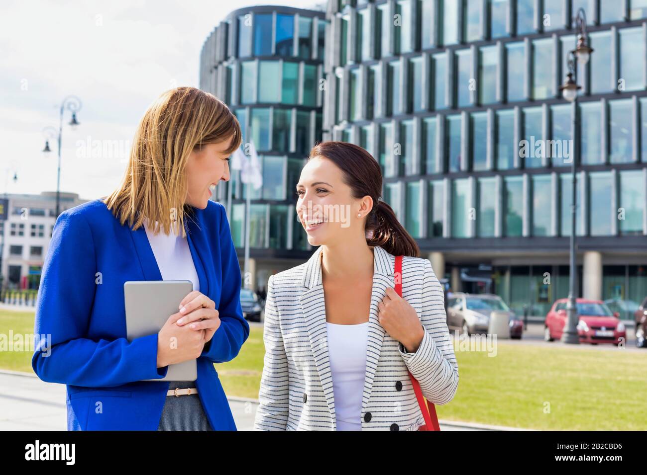 Businesswomen walking while talking outside office building Stock Photo ...