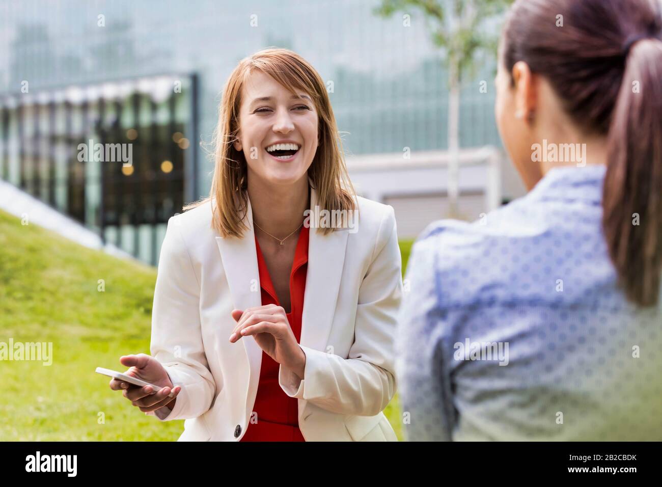 Businesswoman laughing while talking to her colleague Stock Photo - Alamy