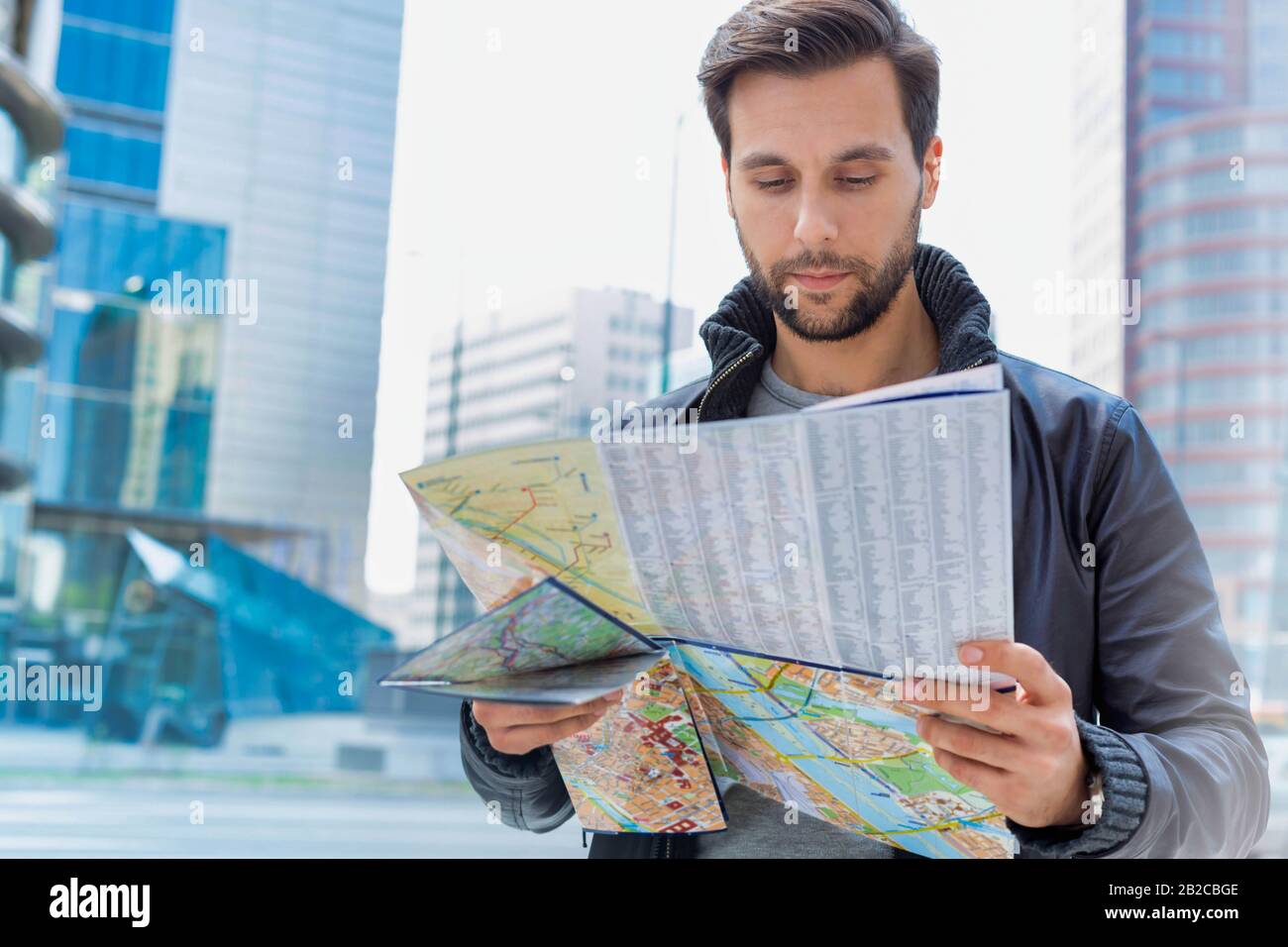 Portrait of young attractive man looking on the map in the city Stock ...