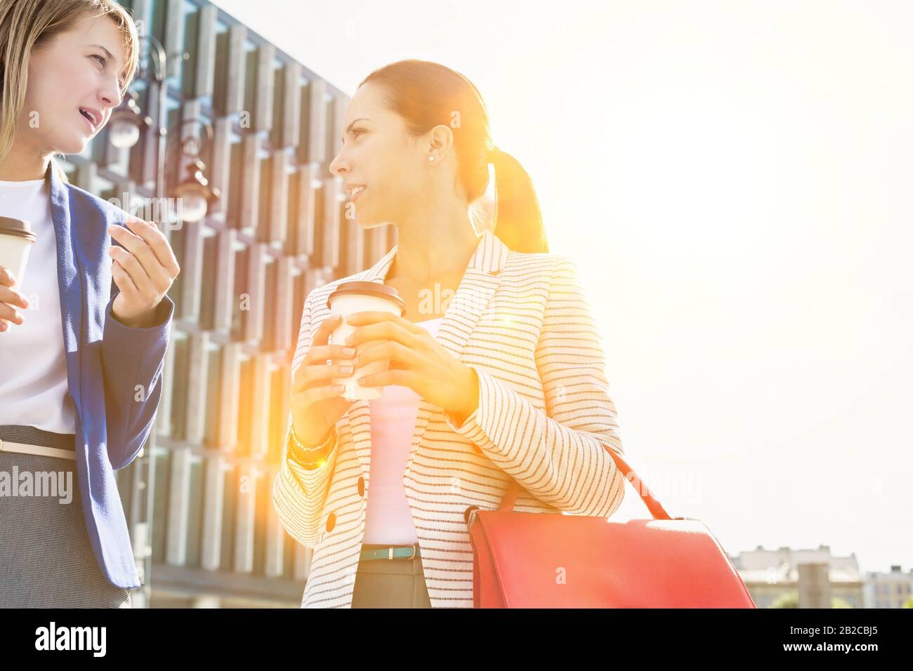 Businesswomen walking while talking outside office building Stock Photo ...