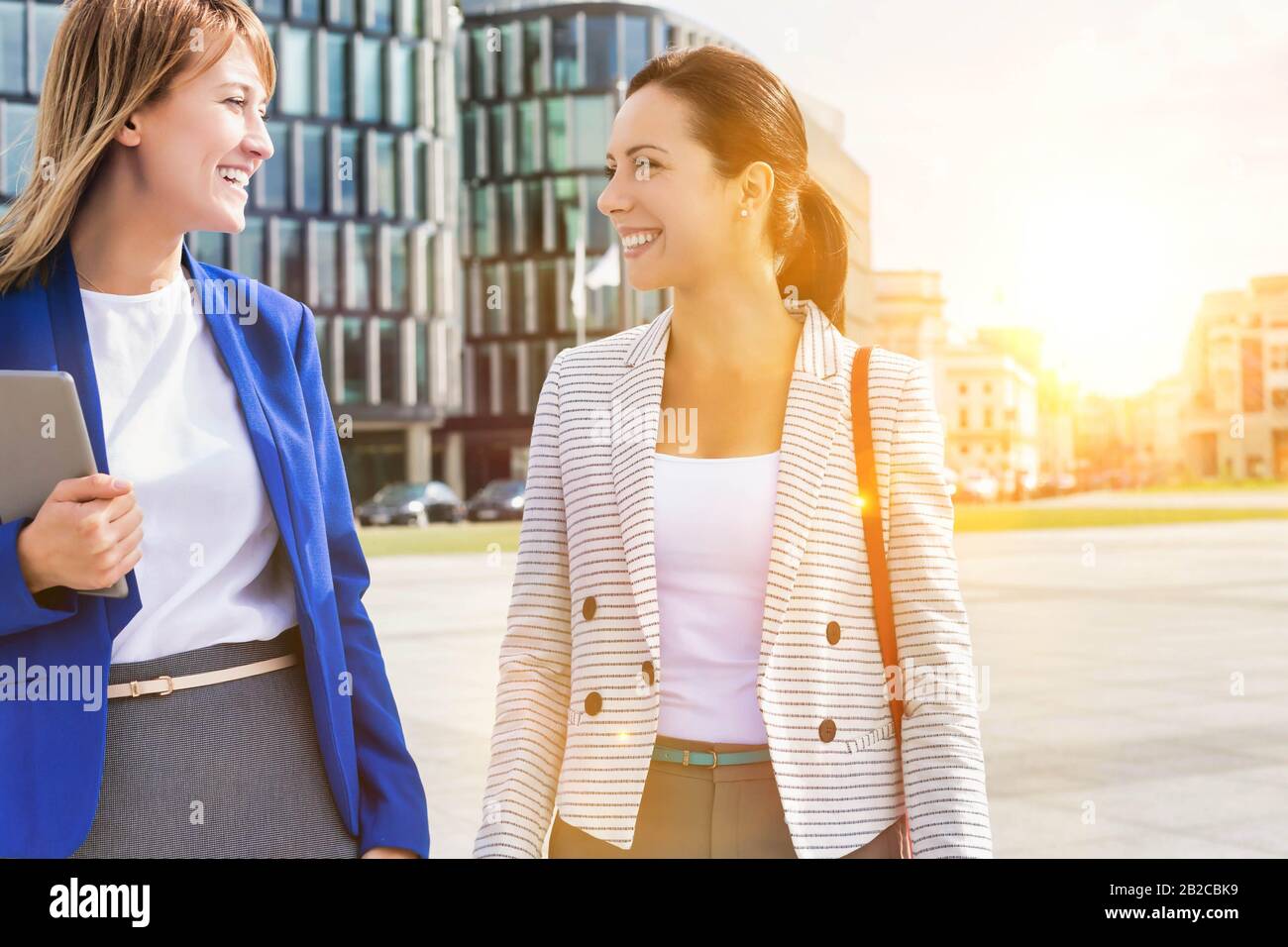 Businesswomen walking while talking outside office building Stock Photo ...