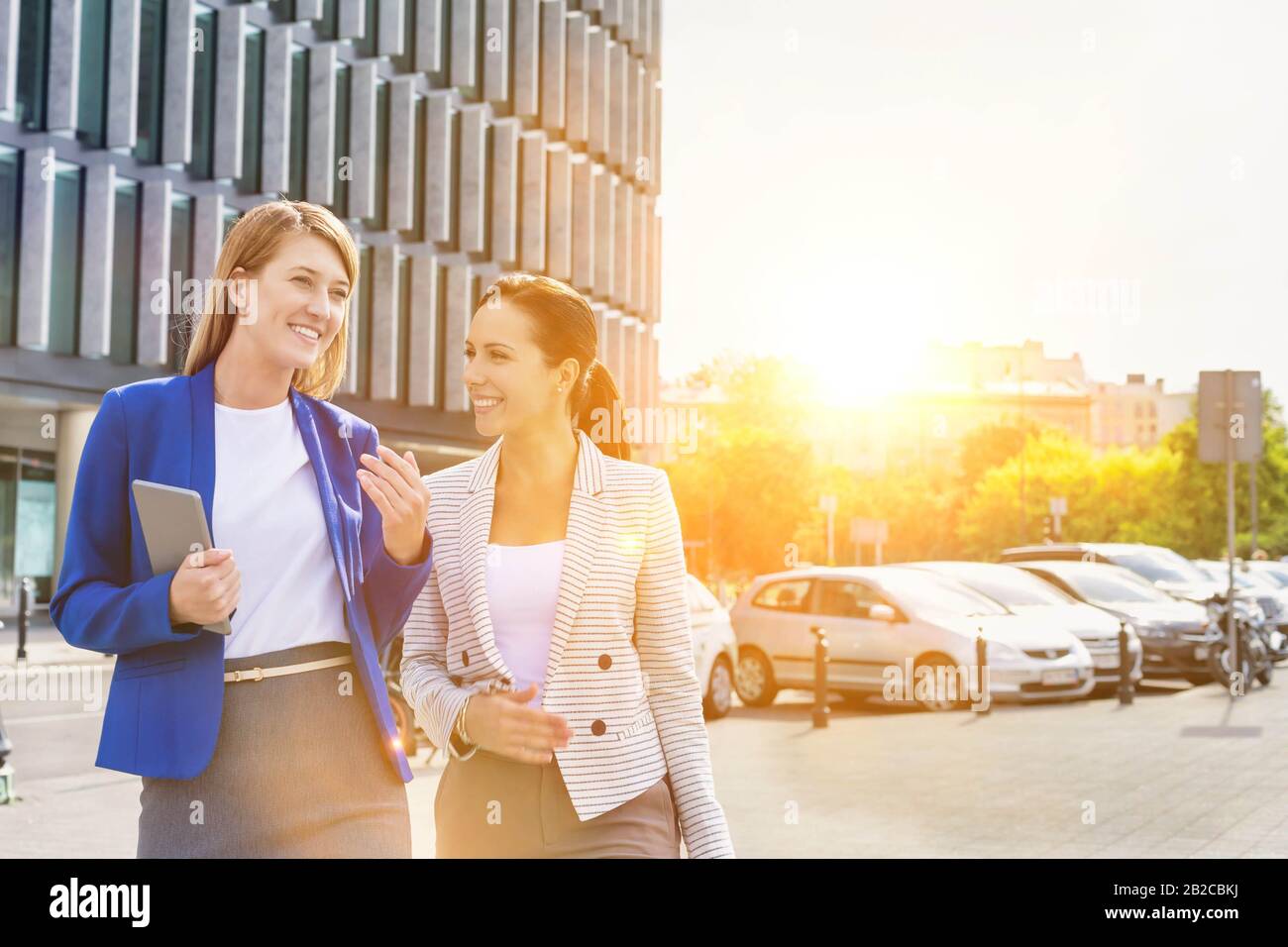 Businesswomen walking while talking outside office building Stock Photo ...