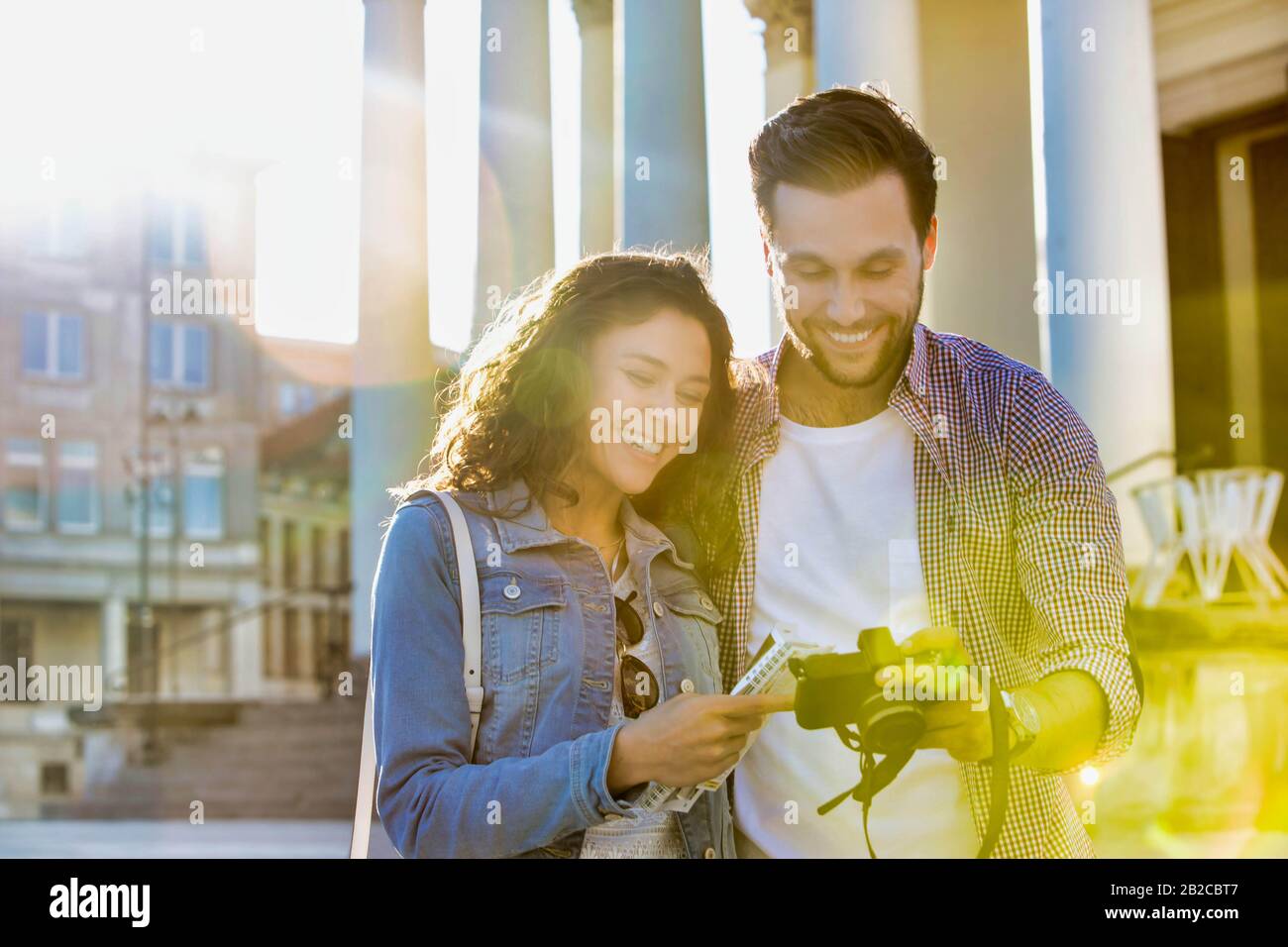 Portrait of handsome young man showing pictures on camera to his ...