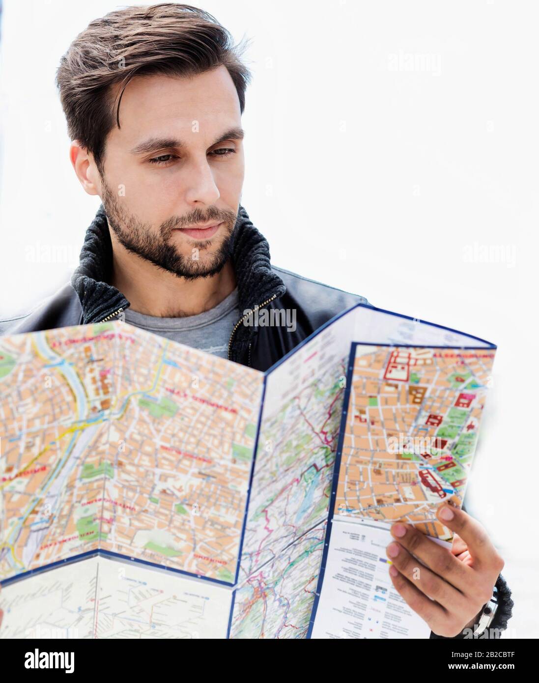 Portrait of young attractive man looking on the map in the city with ...