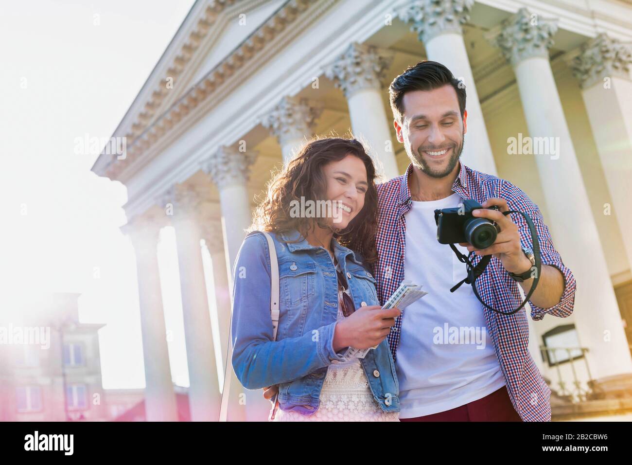 Portrait of handsome young man showing pictures on camera to his ...