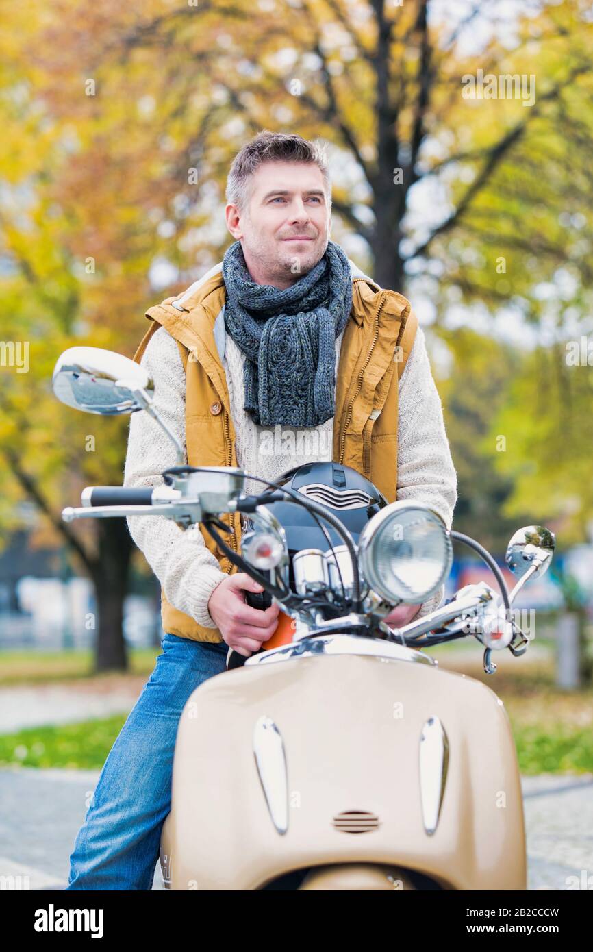Portrait of mature attractive man sitting on motor bike while waiting ...