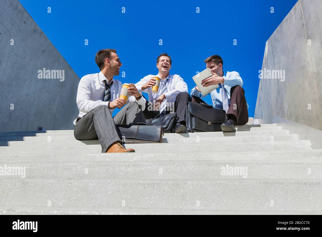 Group of handsome businessman sitting on stairs while talking during ...