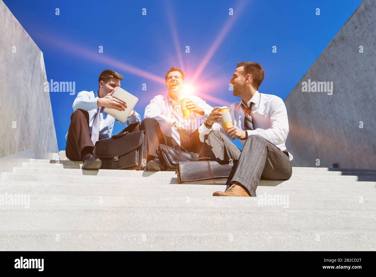 Group of handsome businessman sitting on stairs while talking during ...