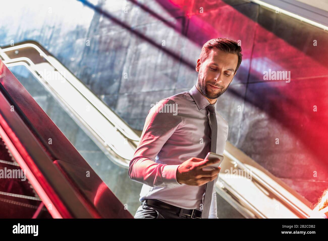 Portrait of young attractive businessman using smartphone while walking ...