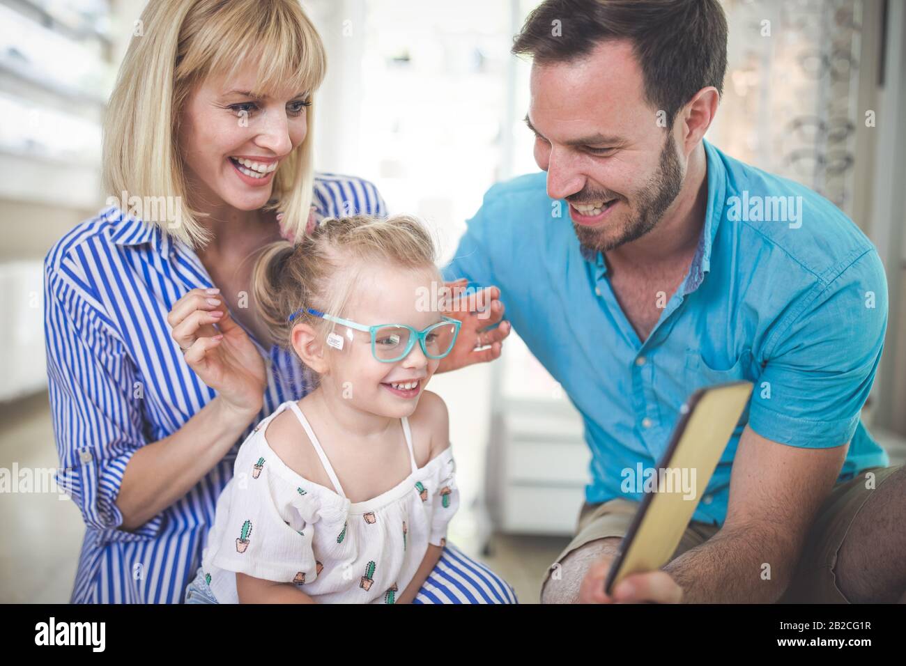 Happy family choosing glasses in optics store Stock Photo - Alamy