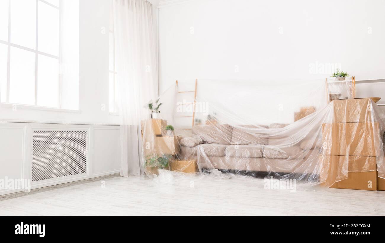 Home renovation in big light room with covered furniture Stock Photo ...