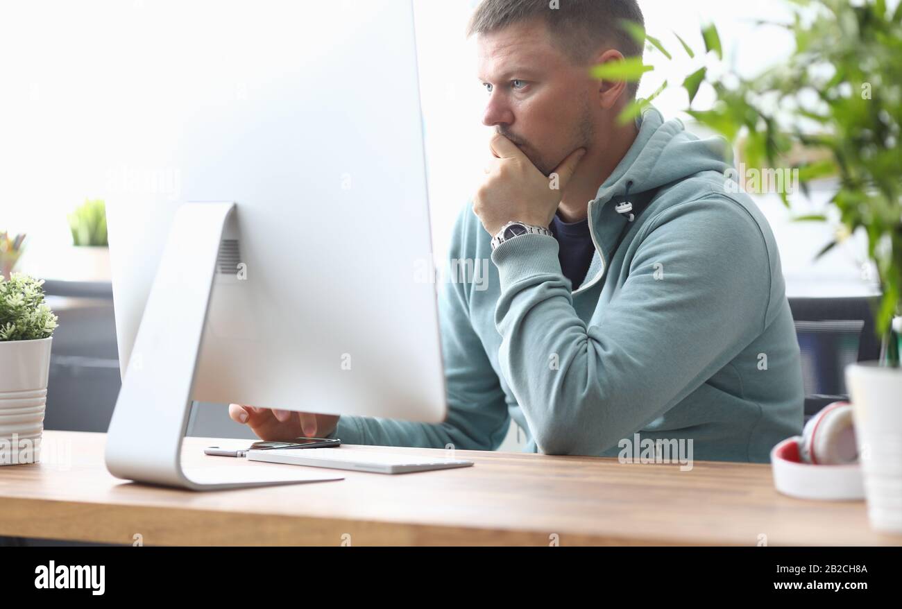 Man sits front computer monitor looking for info Stock Photo - Alamy