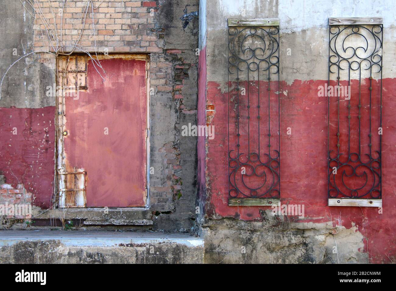a red fadeing painted dirty warehouse in an alley with red door rusted ...