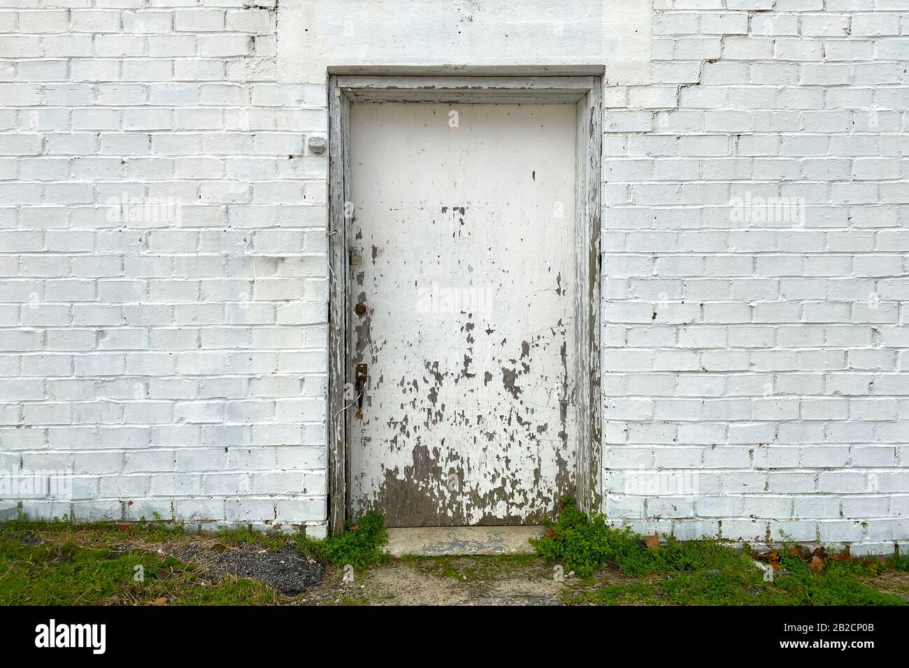 a back alley boarded up doorway with whitewashed brick building in an ...