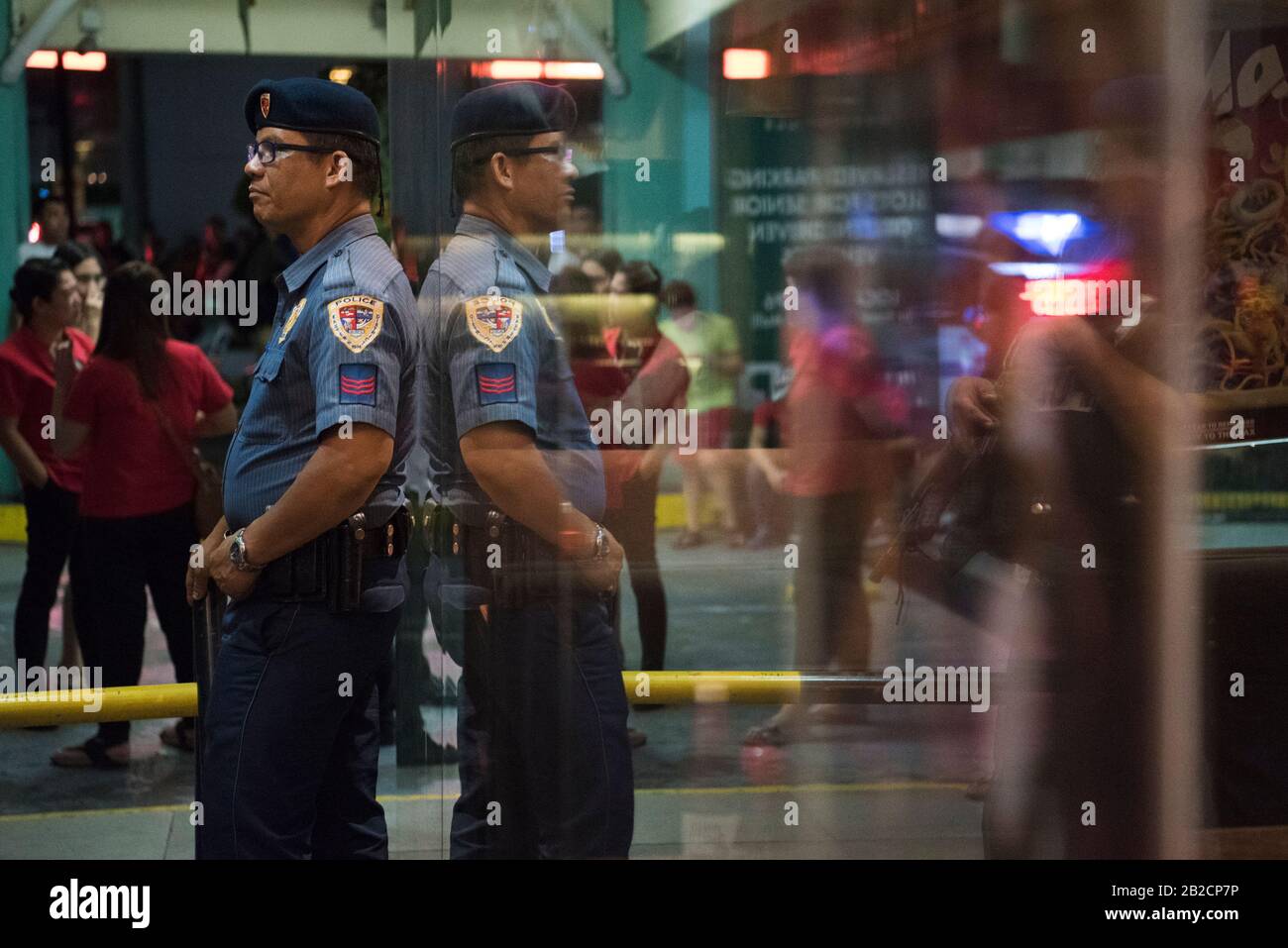 A police officer stands on guard outside V shopping Mall in Manila ...