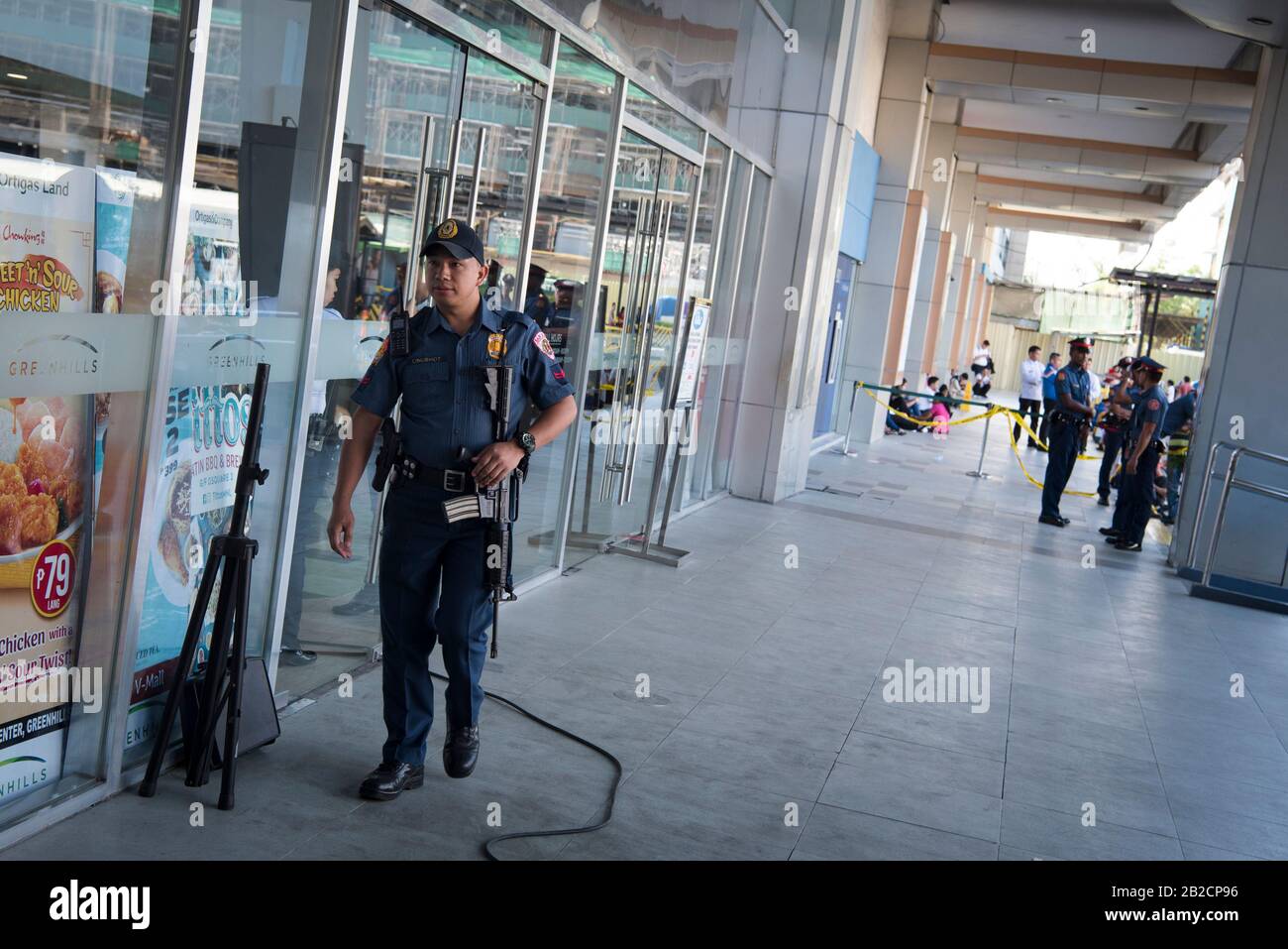 A police officer stands on guard outside V shopping Mall in Manila ...