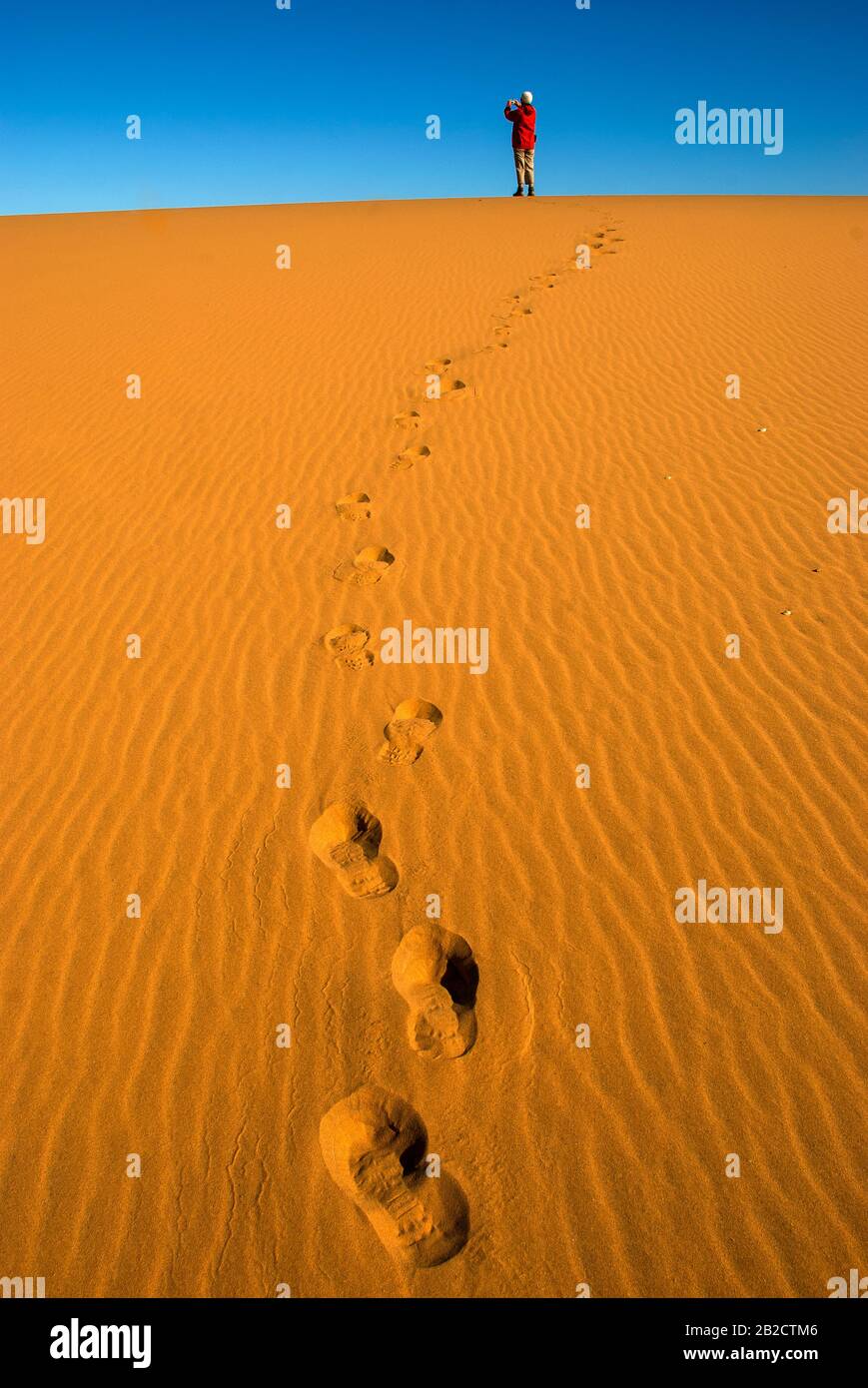 Tourist climbing a dune during a 4X4 day trip vehicle through the red ...
