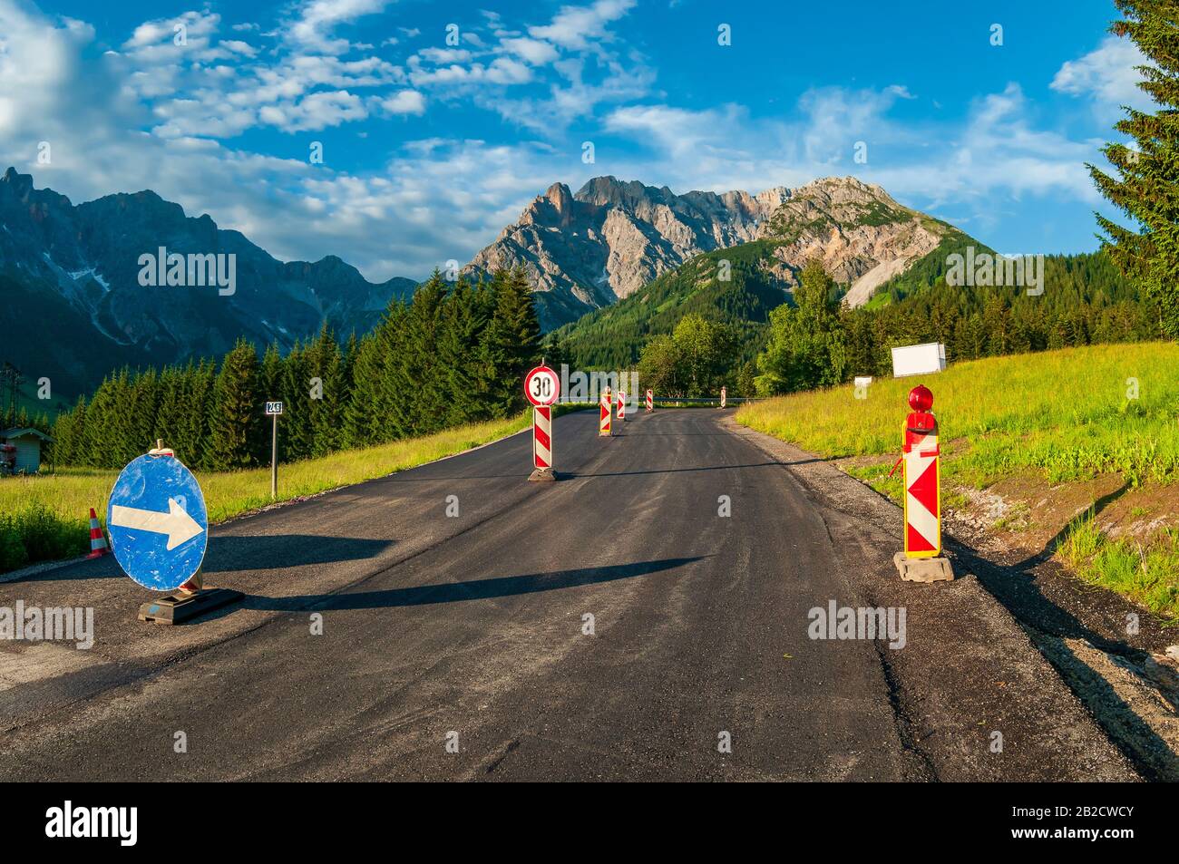 Road works high in the mountains. Narrow alpine road with road signs ...
