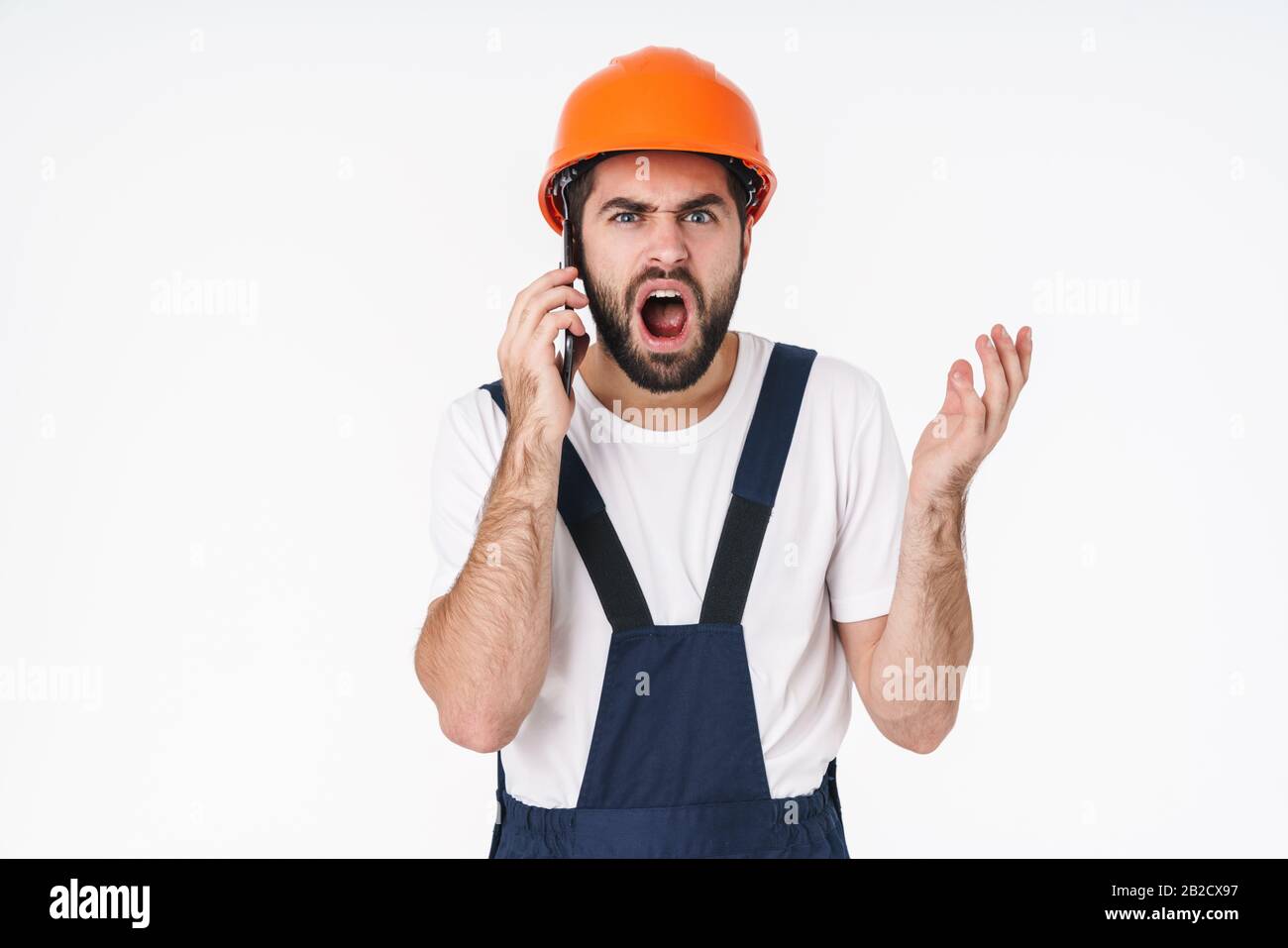 Photo of angry negative young man builder in helmet posing isolated ...