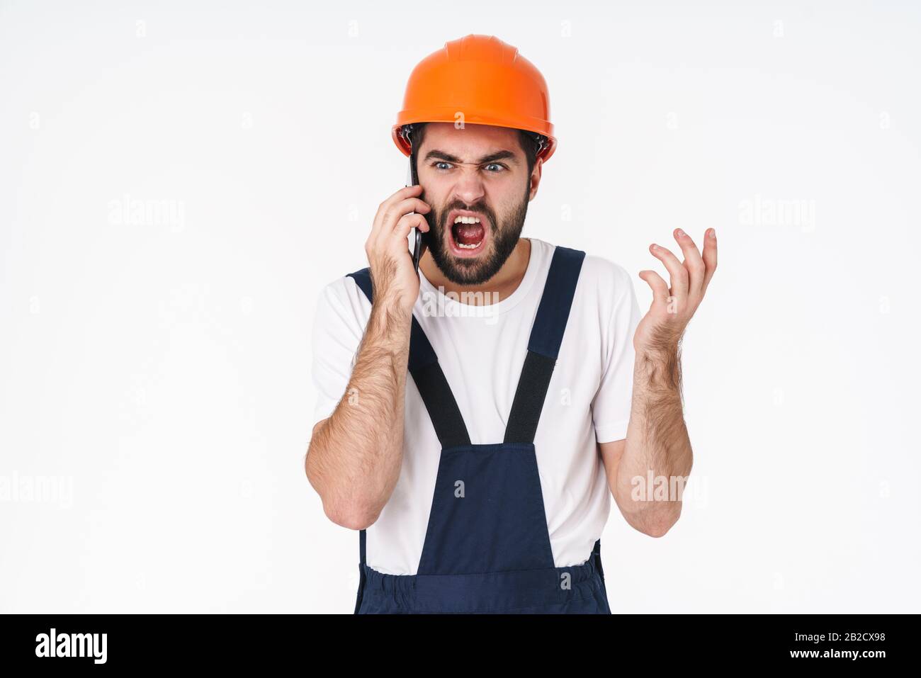 Photo of angry negative young man builder in helmet posing isolated ...