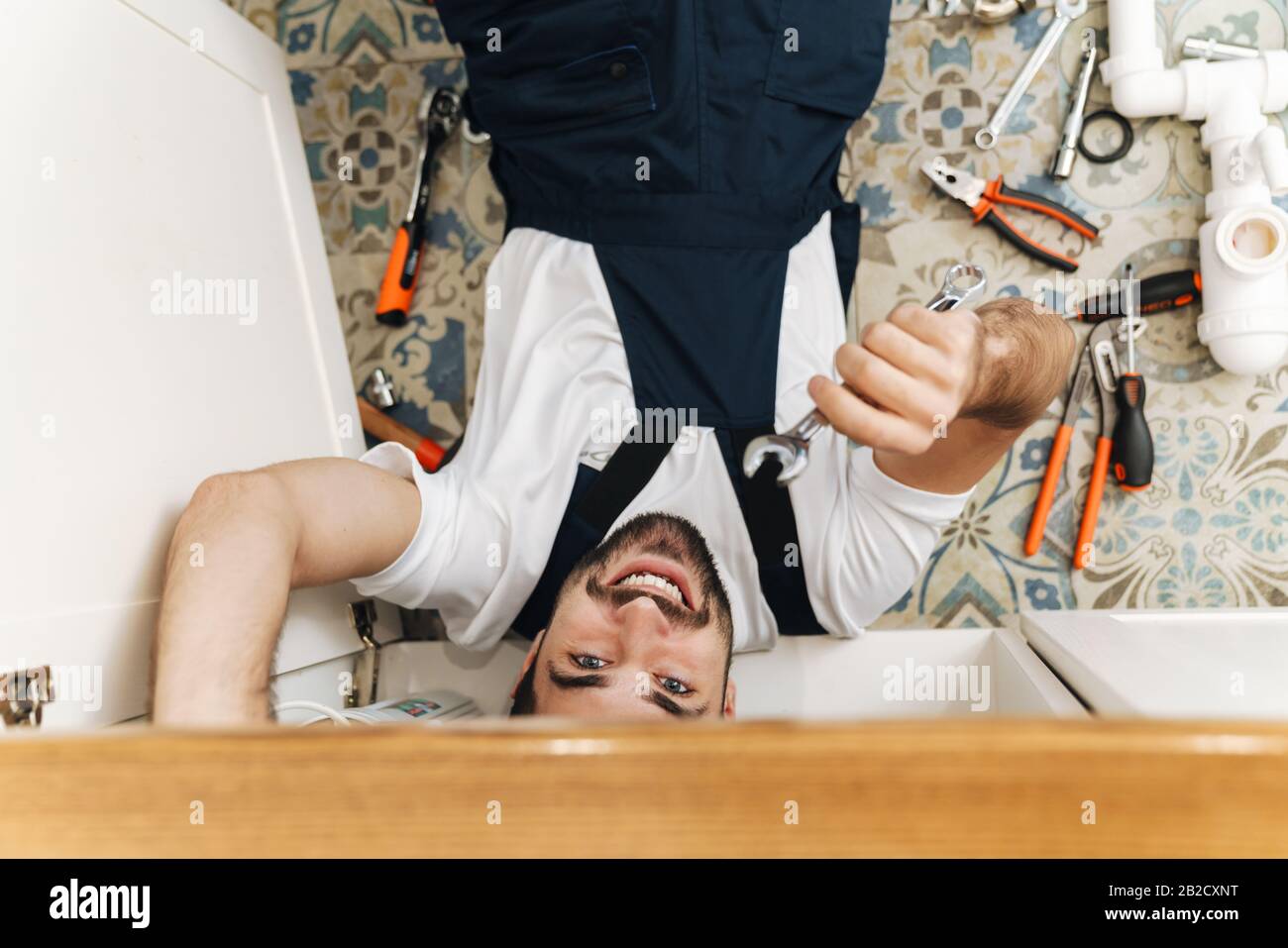Image of a cheerful positive handsome young man plumber work in uniform ...